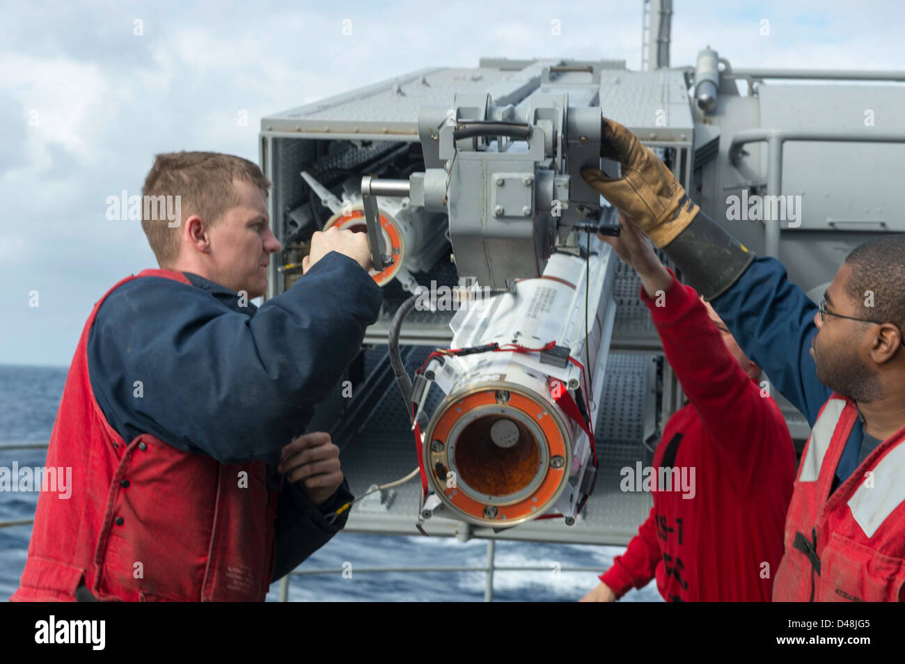 Sailors aboard a U.S. Navy ship load a Sea Sparrow missile as part of a ...