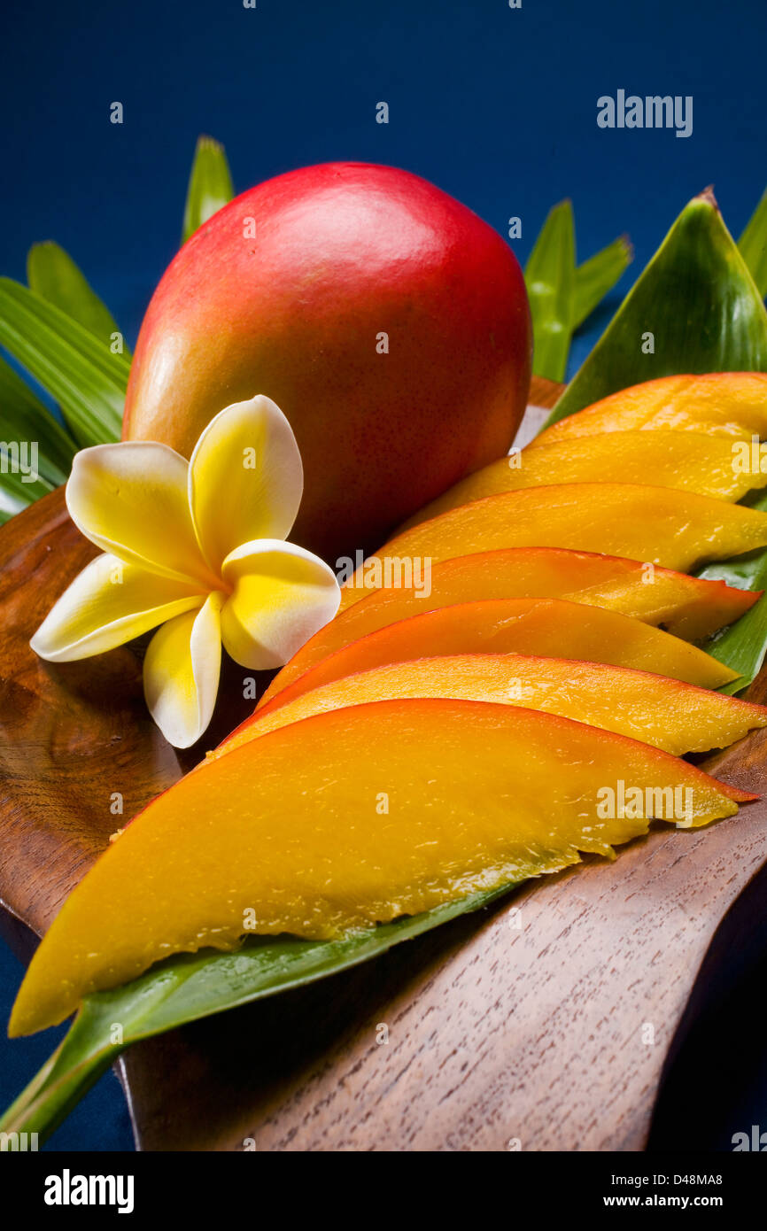 Studio Shot Of Mango, Whole And Cut Into Slices, With Flowers Stock ...