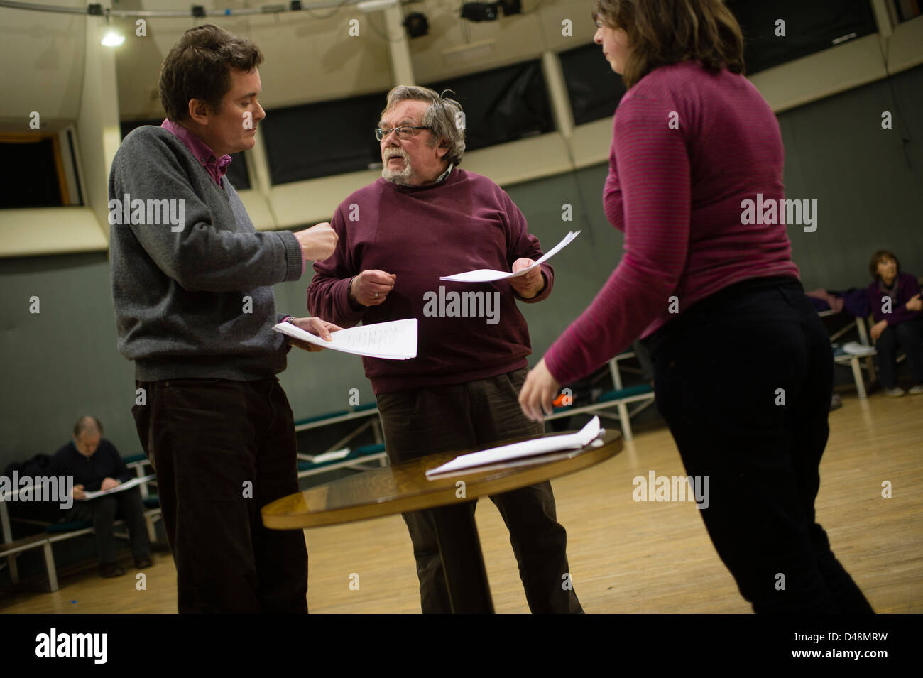 A director with his Actors in rehearsal, holding their scripts, reading ...