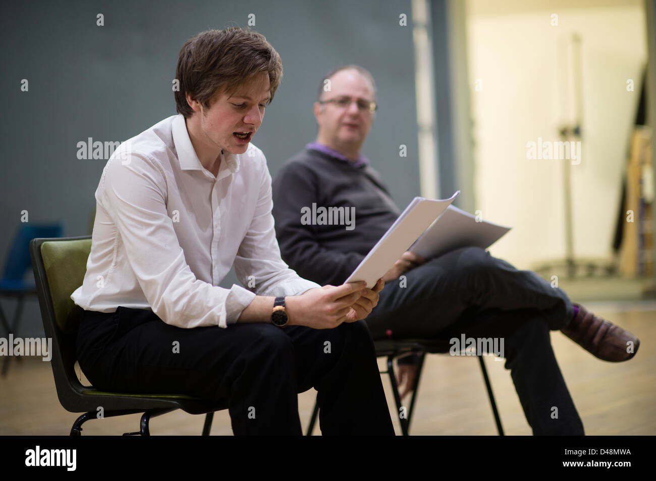 Actors in rehearsal, holding their scripts, reading lines of dialogue ...