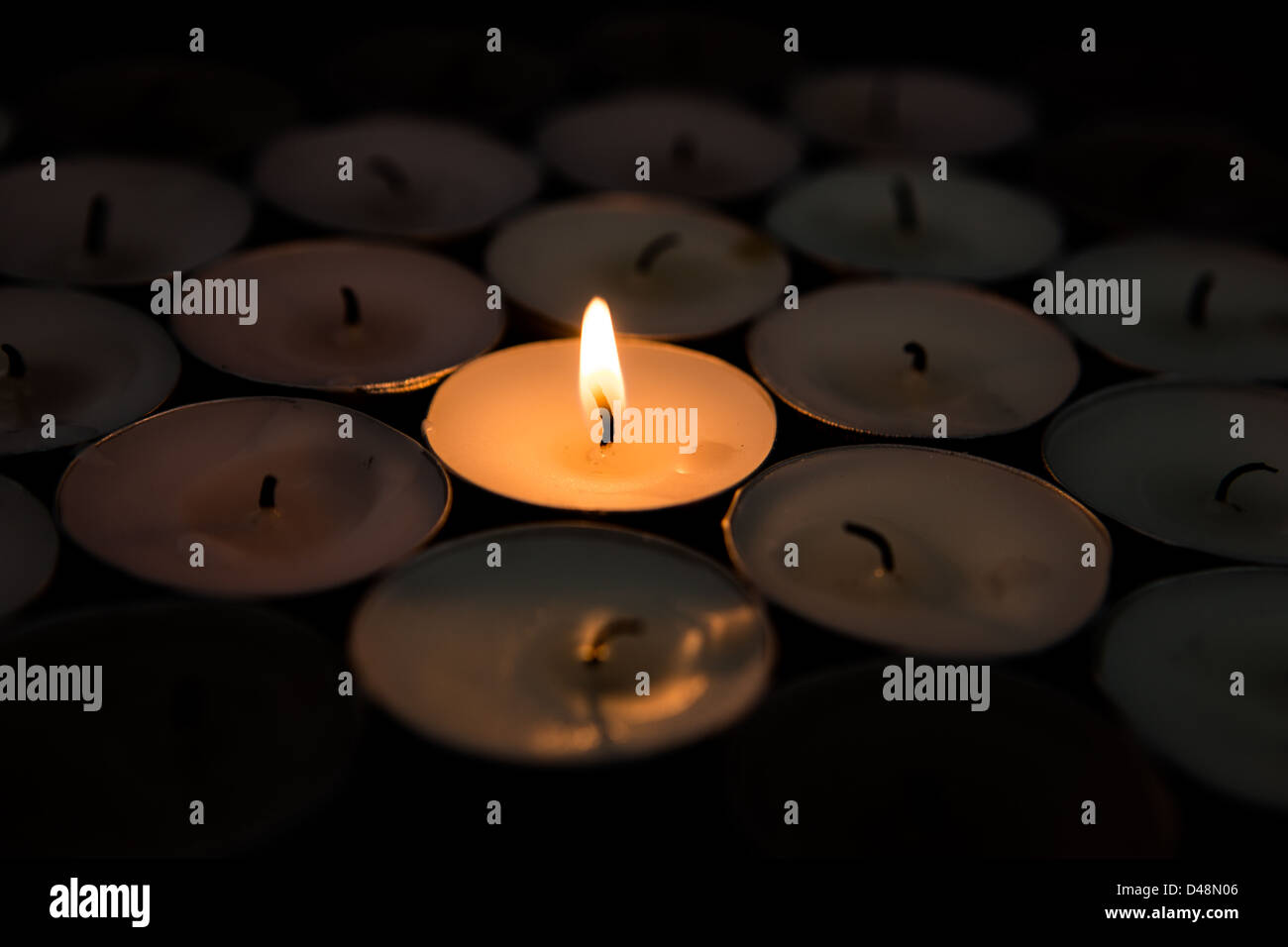 Single candle lighting surrounded by others Stock Photo - Alamy
