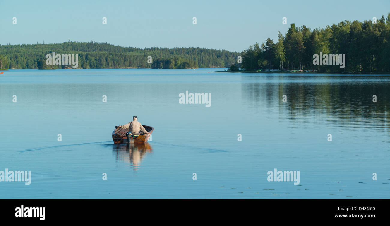 Old man in a small motorized boat moving away on a lake Stock Photo - Alamy