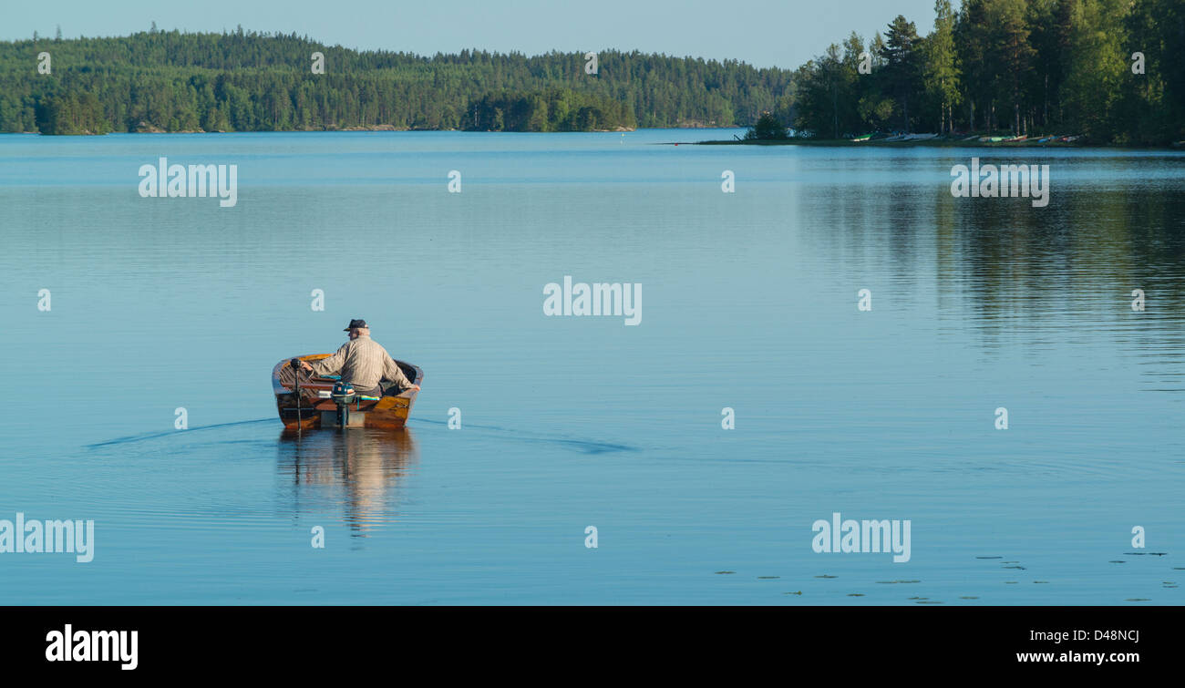 Old man in a small motorized boat moving away on a lake Stock Photo - Alamy