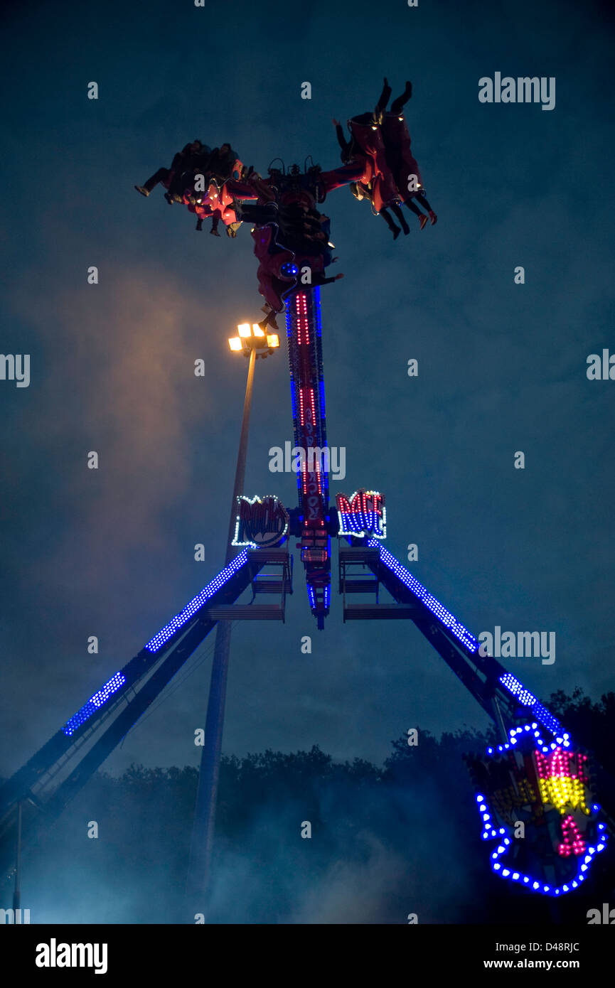 People upside down on a spectacular fairground ride in the evening with ...