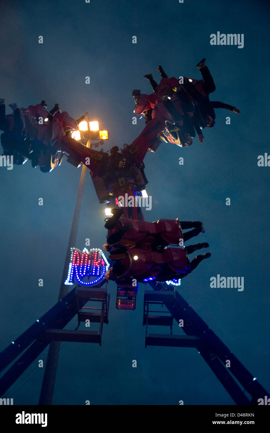 People upside down on a spectacular fairground ride in the evening with ...