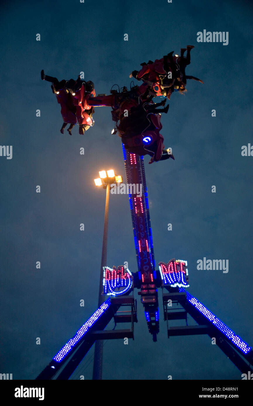 People upside down on a spectacular fairground ride in the evening with ...