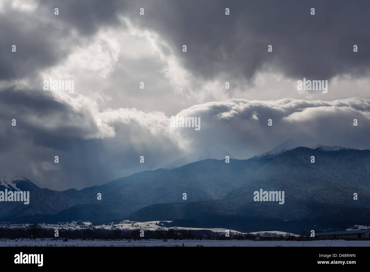 Gleam in clouds of a snow storm over mountains Stock Photo - Alamy