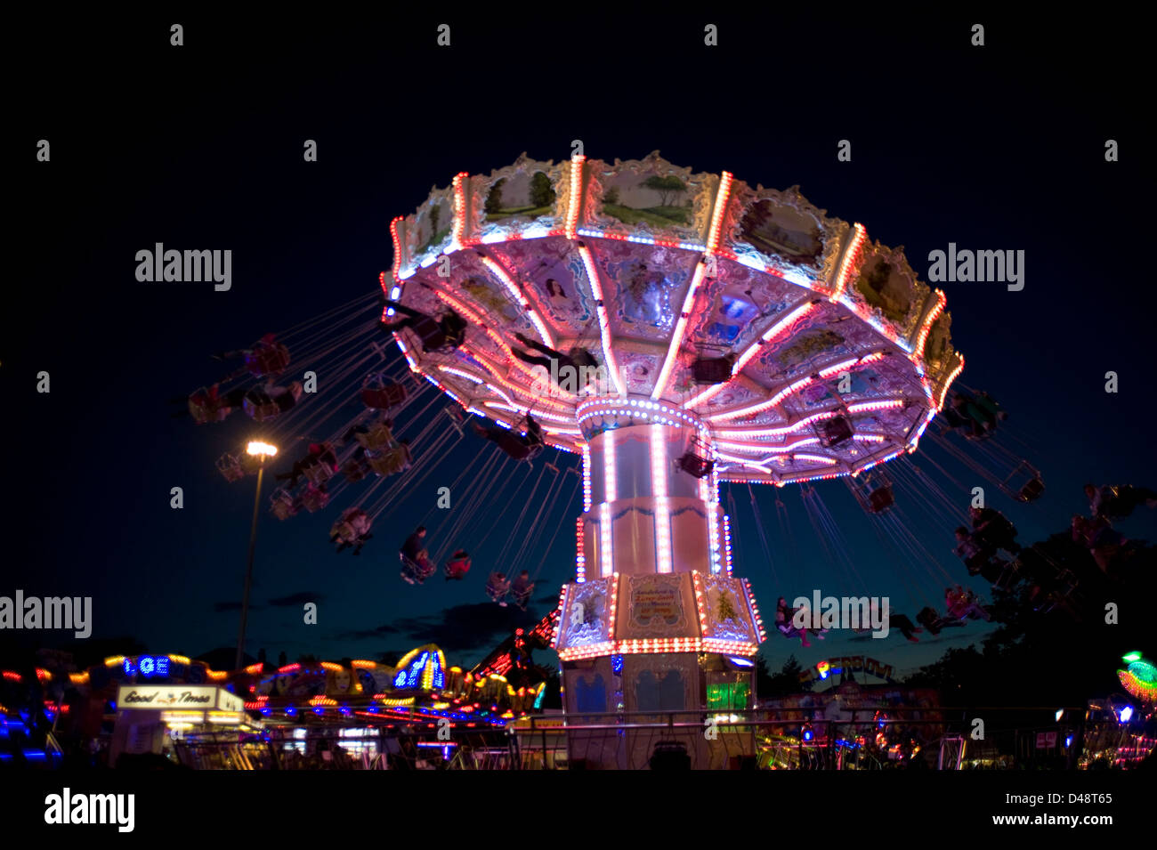 A spectacular fairground chair ride at night with people swinging ...