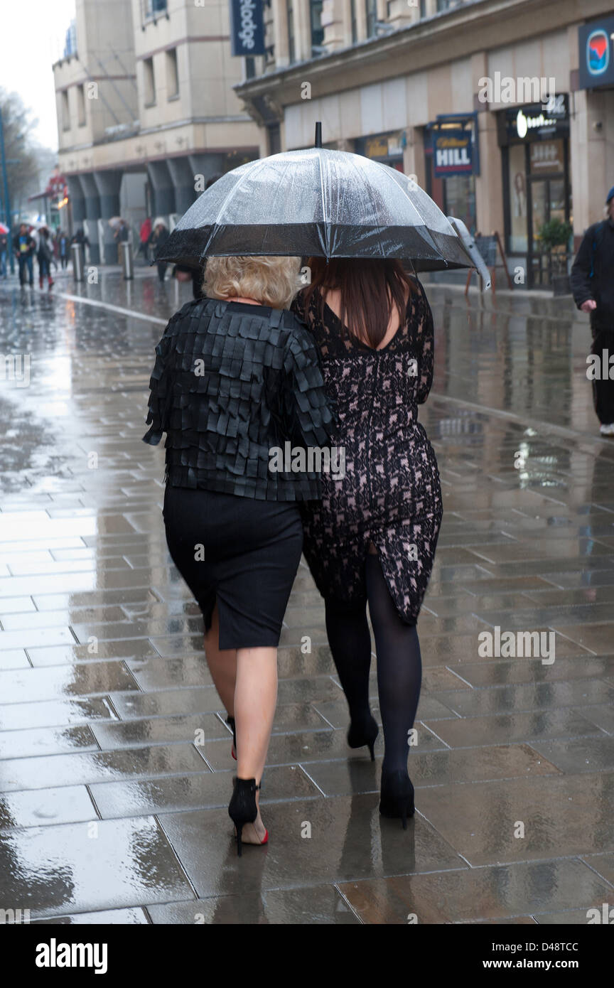 Cardiff, UK. 8th March 2013. Two young women walk under an umbrella ...