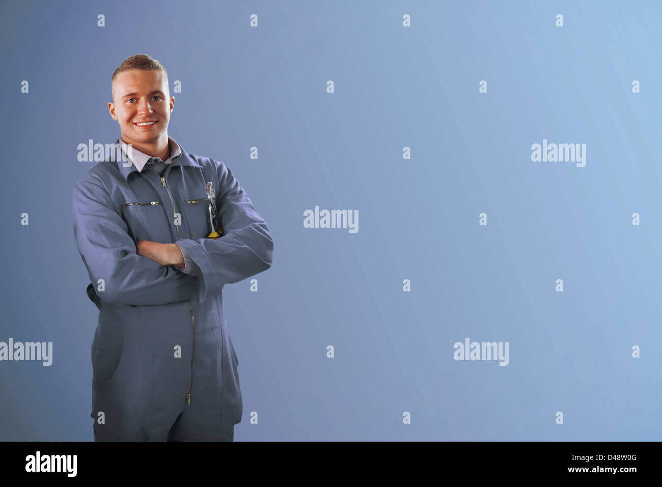 Mechanic standing in front of a blue background Stock Photo - Alamy