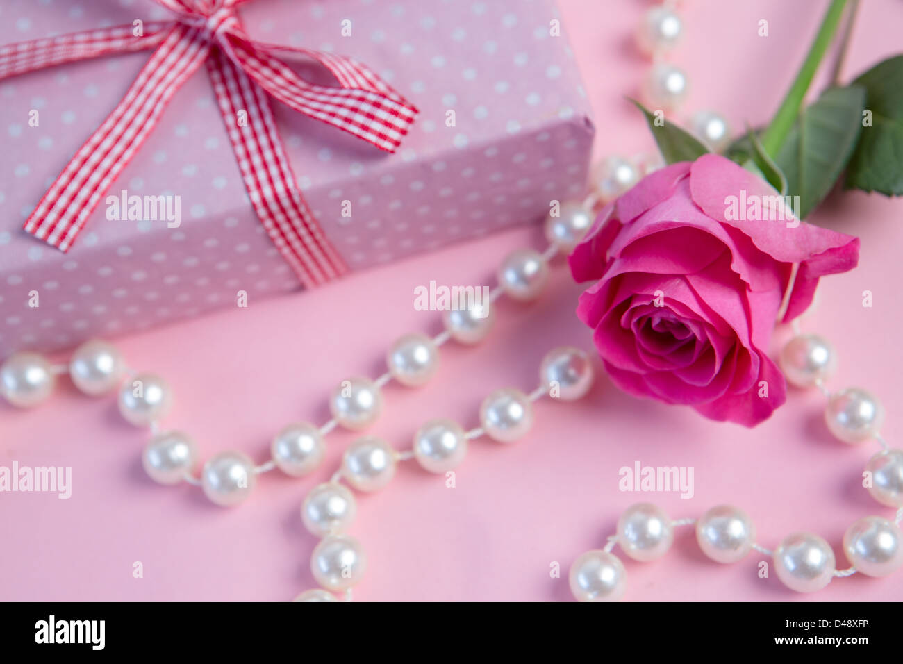 Pink rose with gift and string of pearls Stock Photo - Alamy