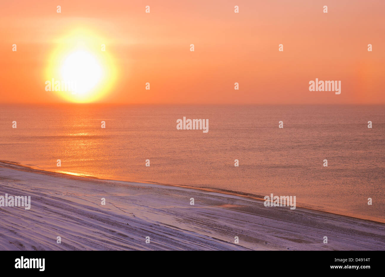 The setting sun shining through windblown snow creates a sundog above ...
