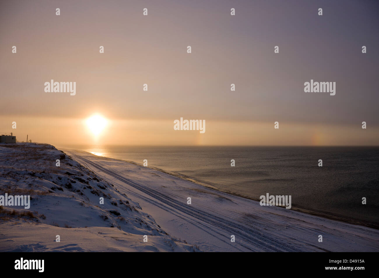 The setting sun shining through windblown snow creates two sundogs ...