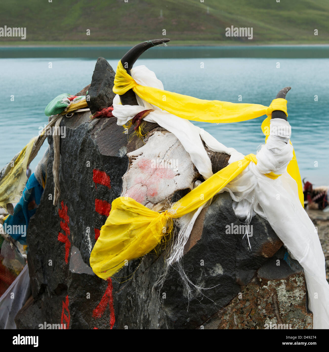 Colourful fabric tied to a rock formation and horns on the water's edge ...