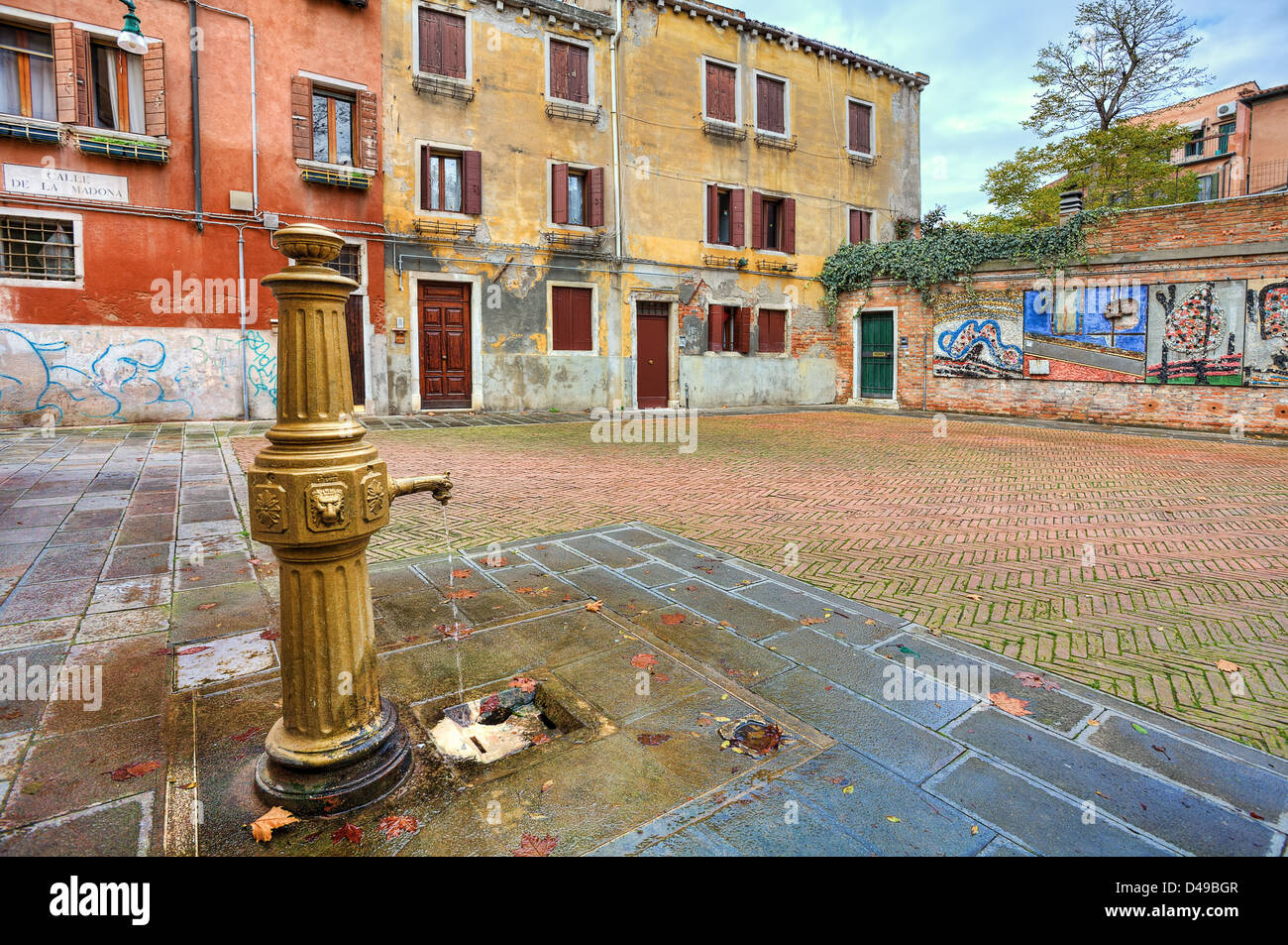 Water pump on courtyard among old traditional venetian colorful houses ...