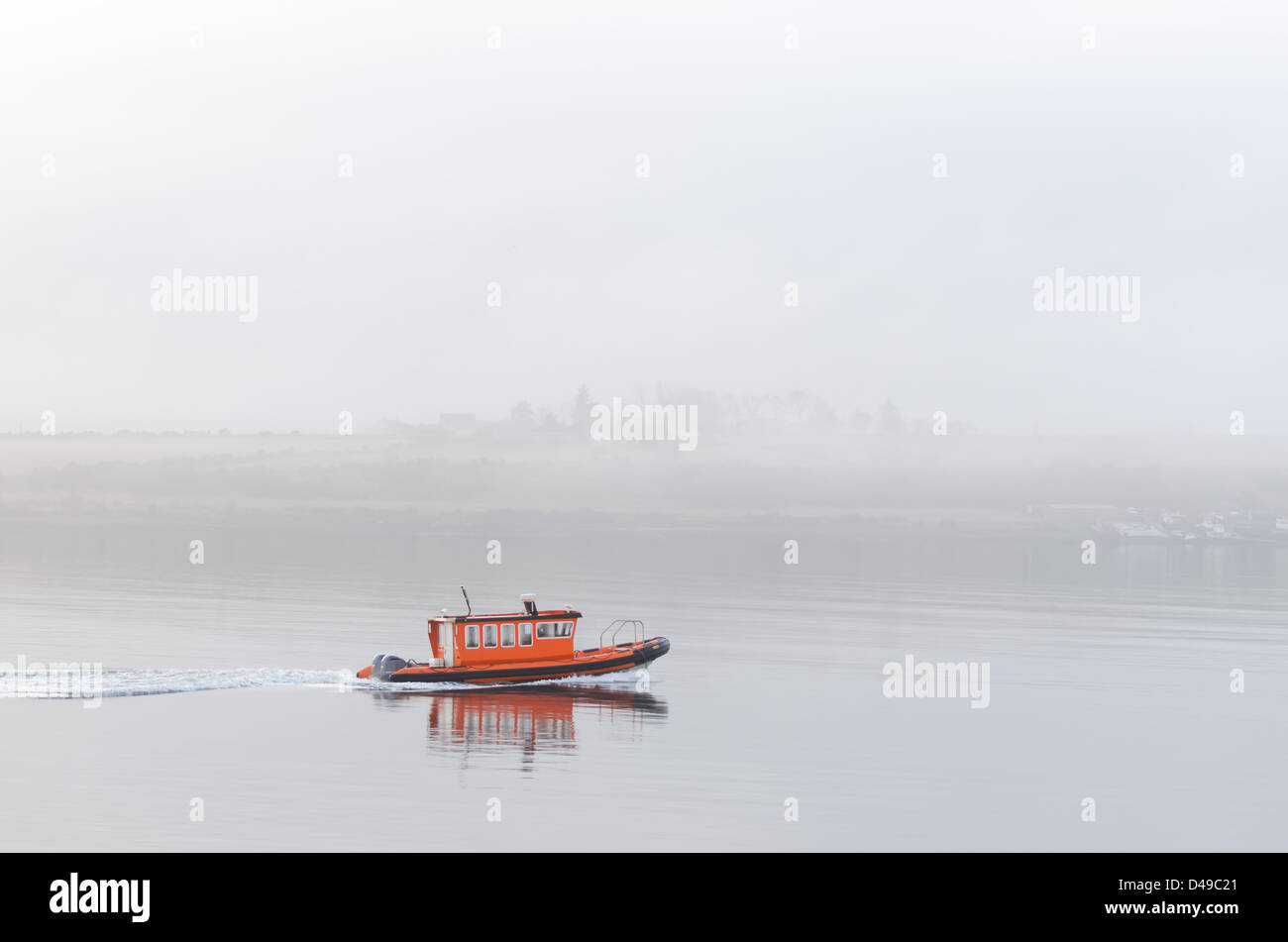 Small lone orange boat sailing in mist Stock Photo - Alamy