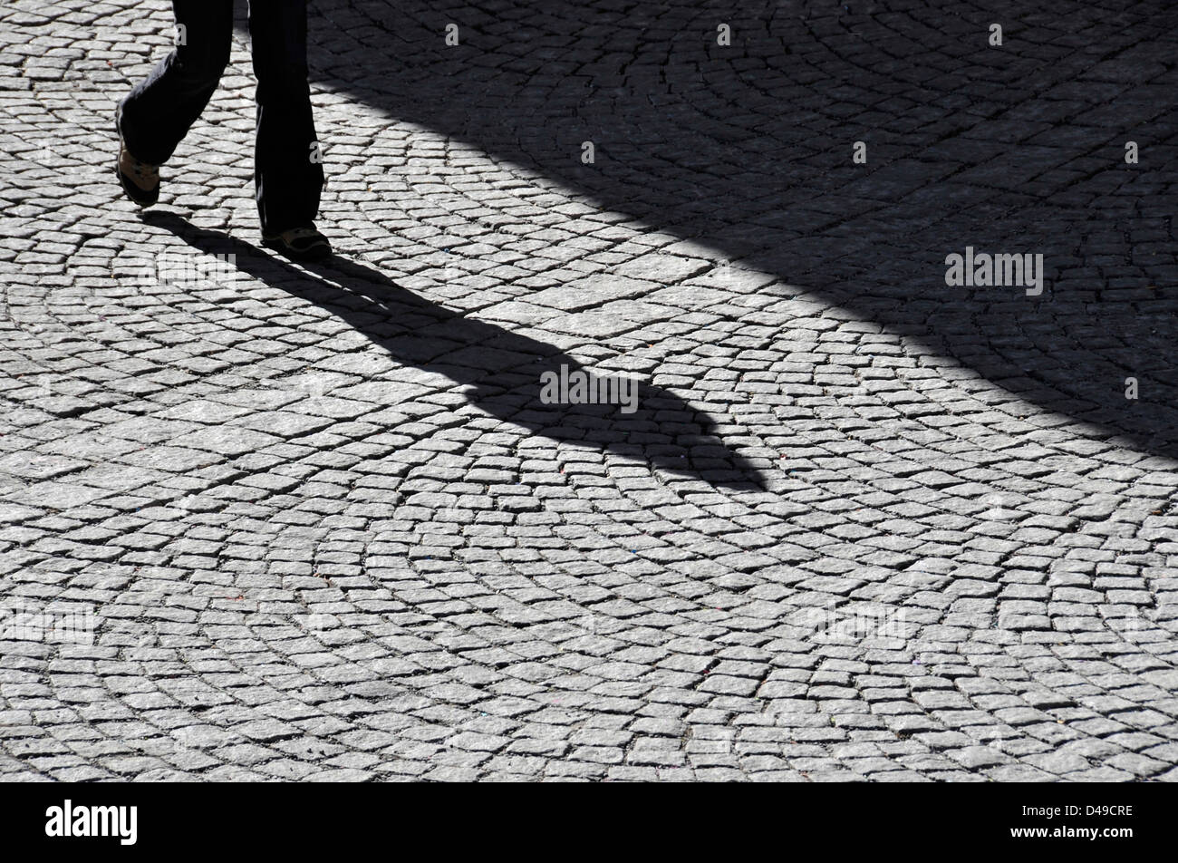 Person casting a shadow on a cobbled street Stock Photo - Alamy