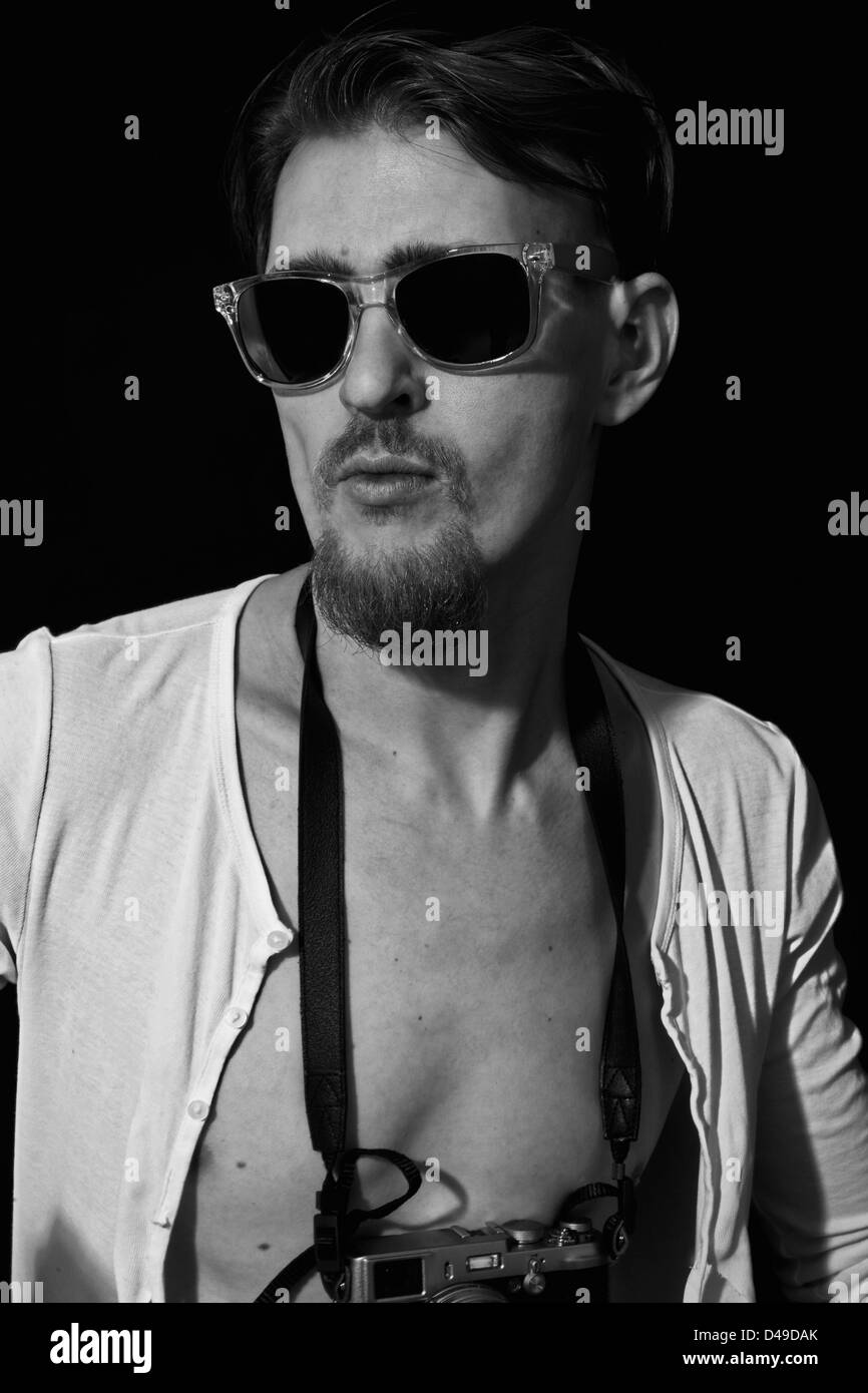 Studio portrait of a young man with a camera on a black background ...