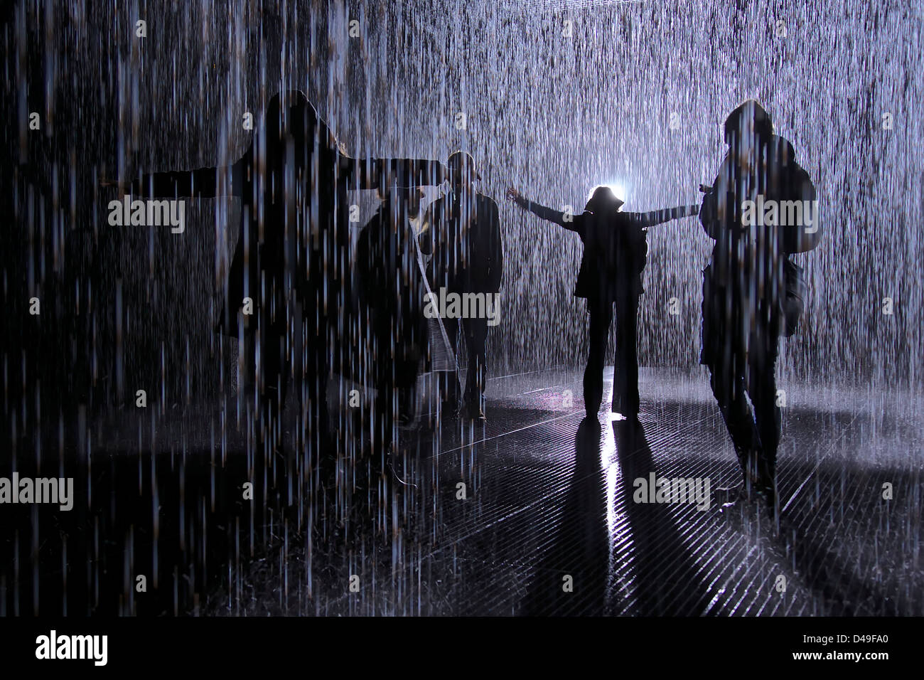 People standing under artificial rain in the Rain Room Exhibition at ...