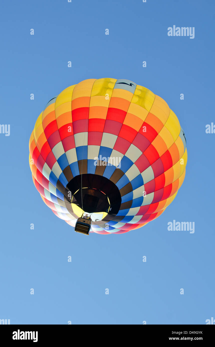 A brightly-colored hot air balloon rises into a clear blue sky Stock ...