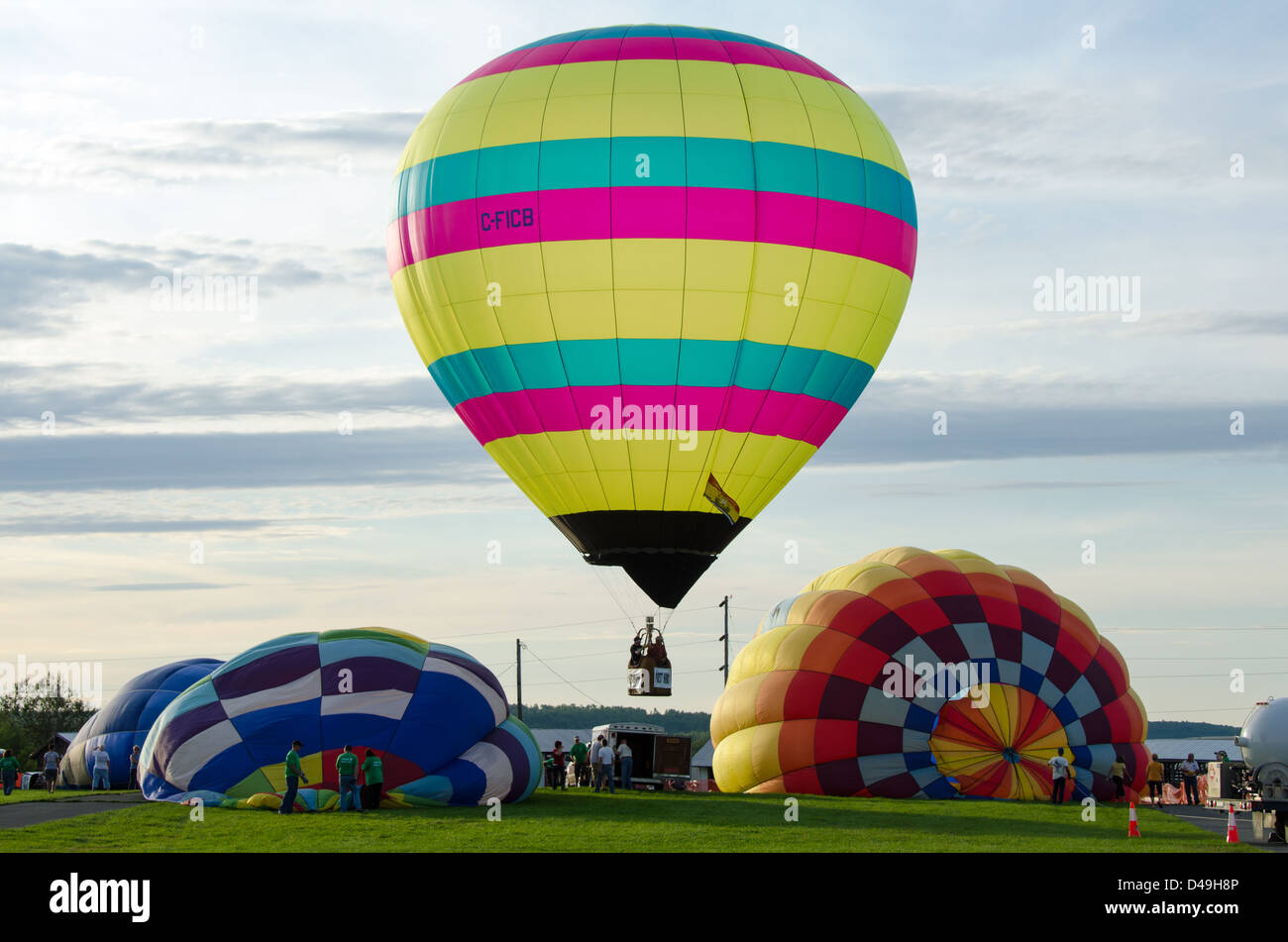 A hot air balloon ascends at evening as two others slowly inflate Stock ...