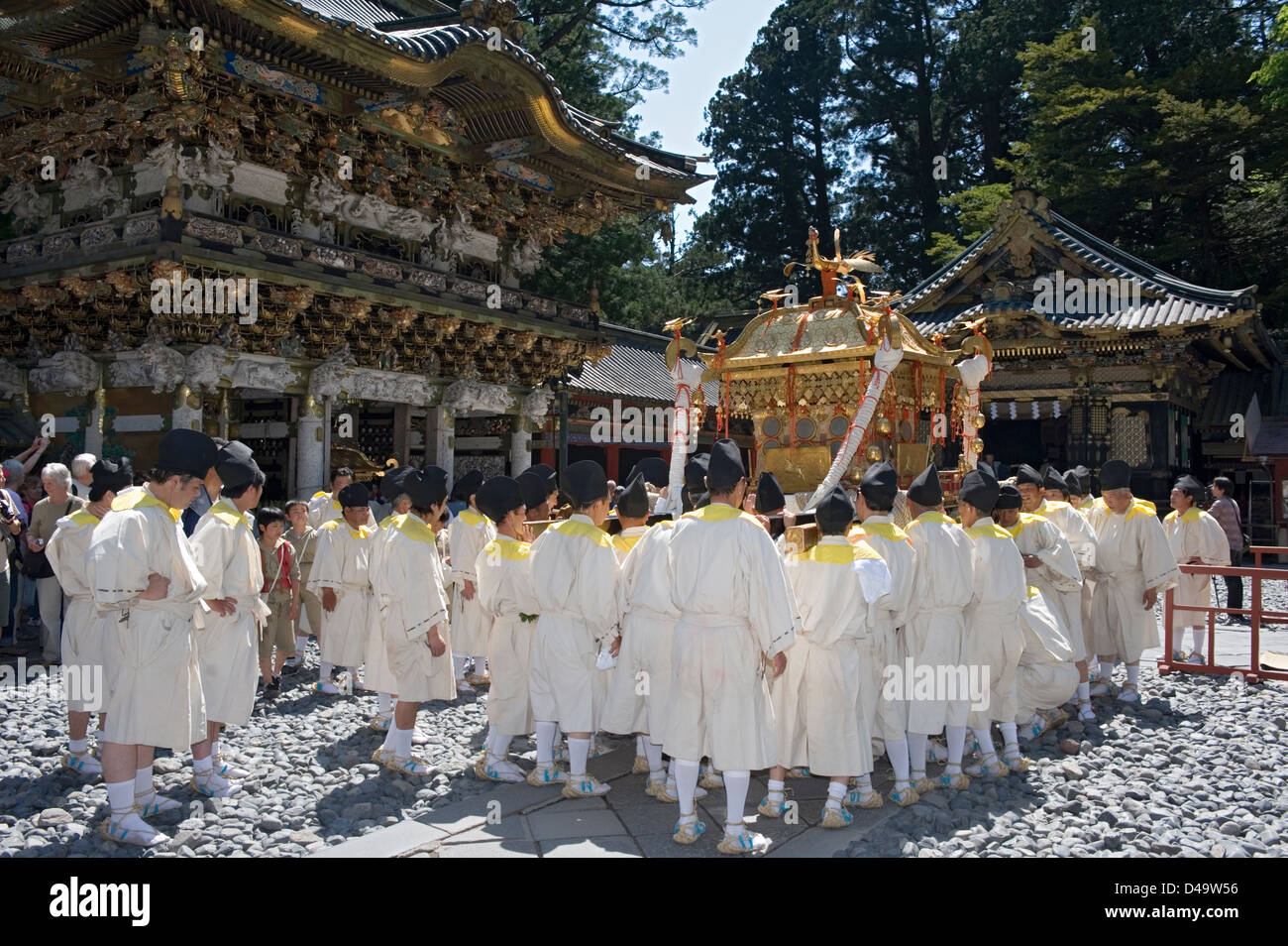 Festival participants in white robes surround a mikoshi portable shrine ...
