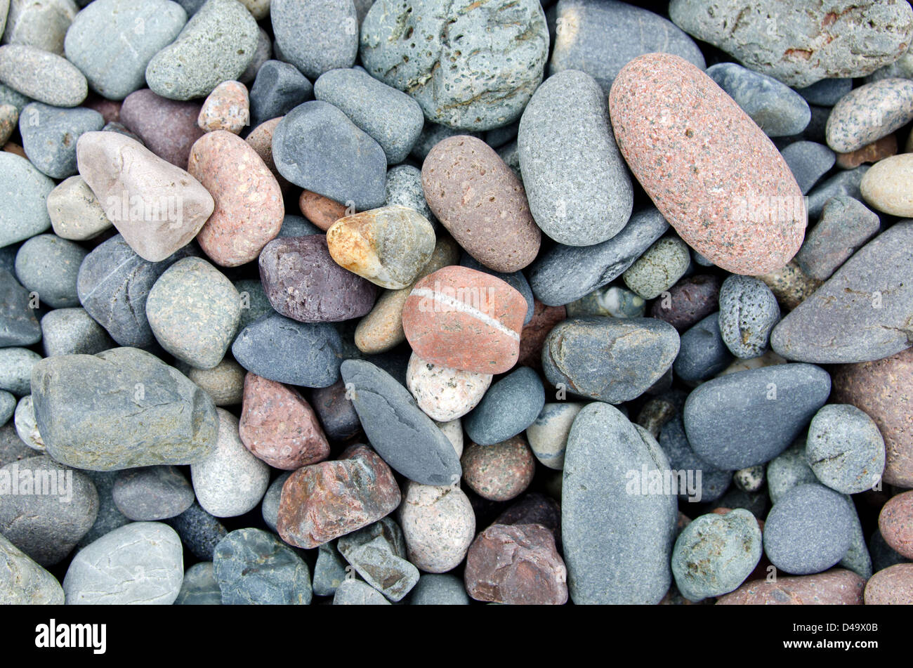 Rounded striped and speckled beach stones in shades of pink and grey at ...