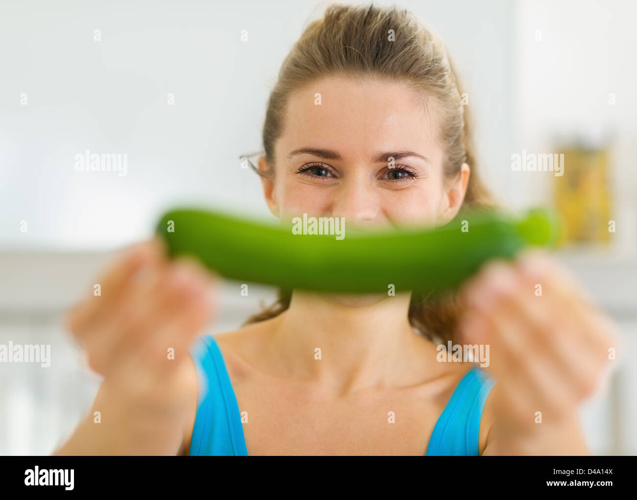 Young woman smiling with zucchini Stock Photo - Alamy