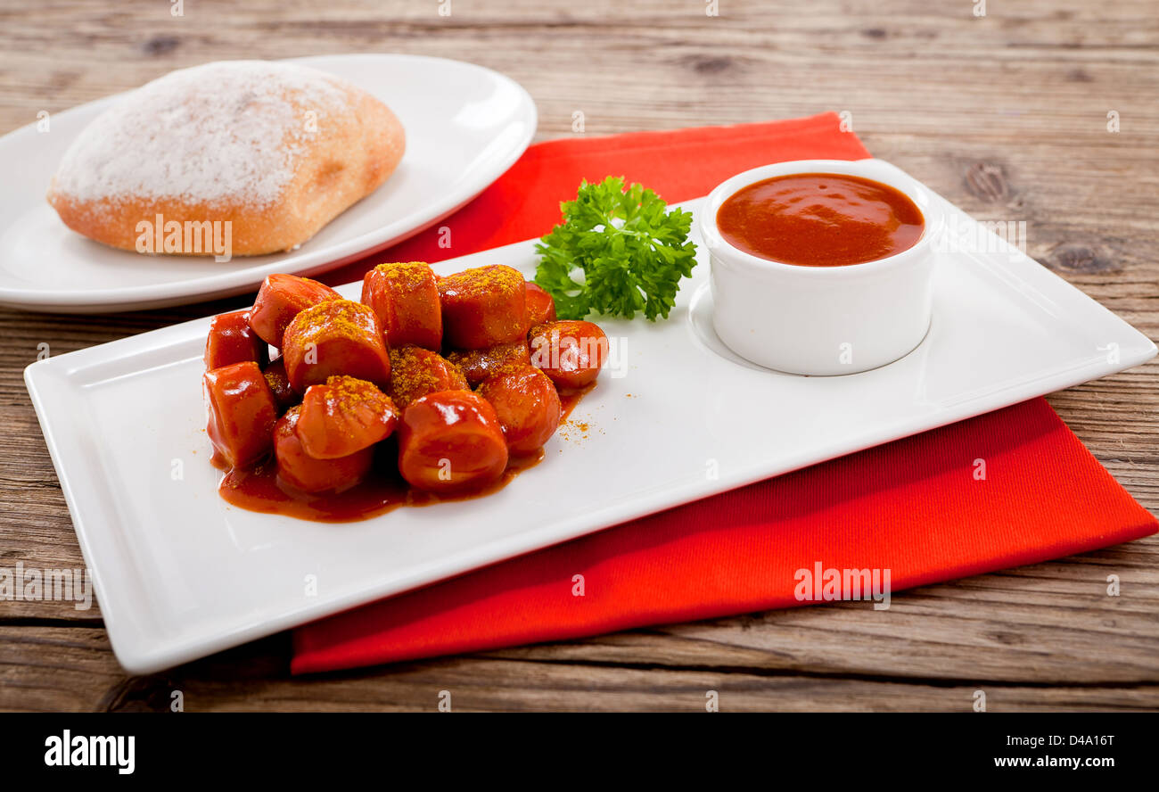 curry wurst spicy sausage with curry and ketchup on wooden background ...