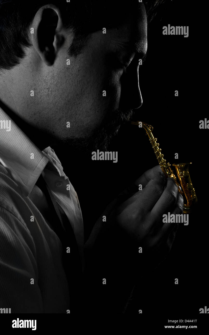 A young man playing a miniature saxophone Stock Photo - Alamy