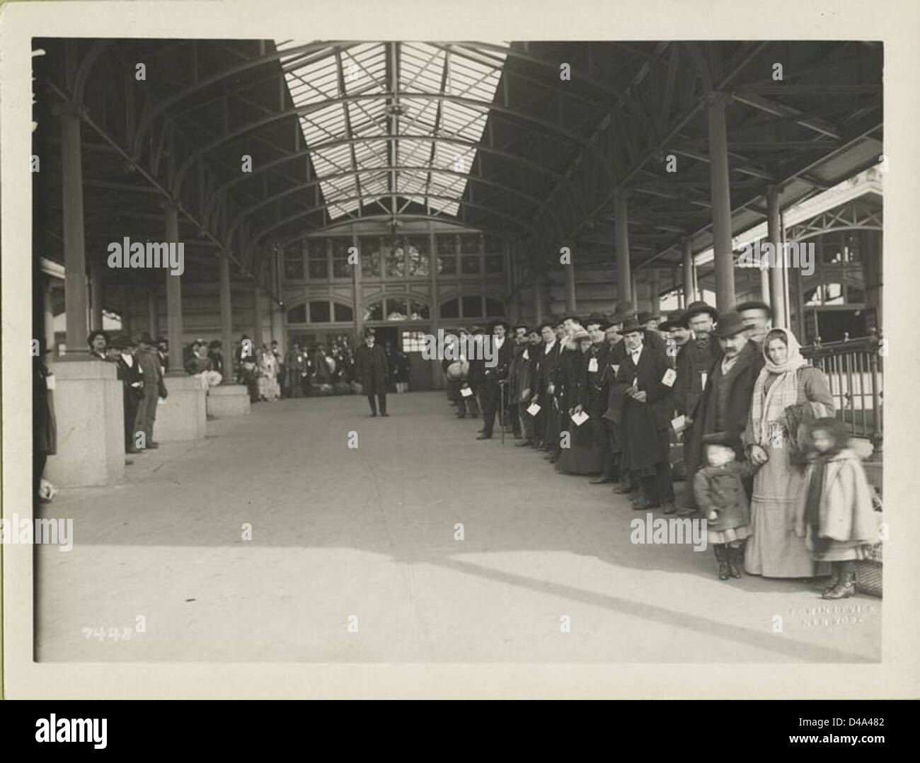 This photograph from around 1910 shows immigrants passing through Ellis ...