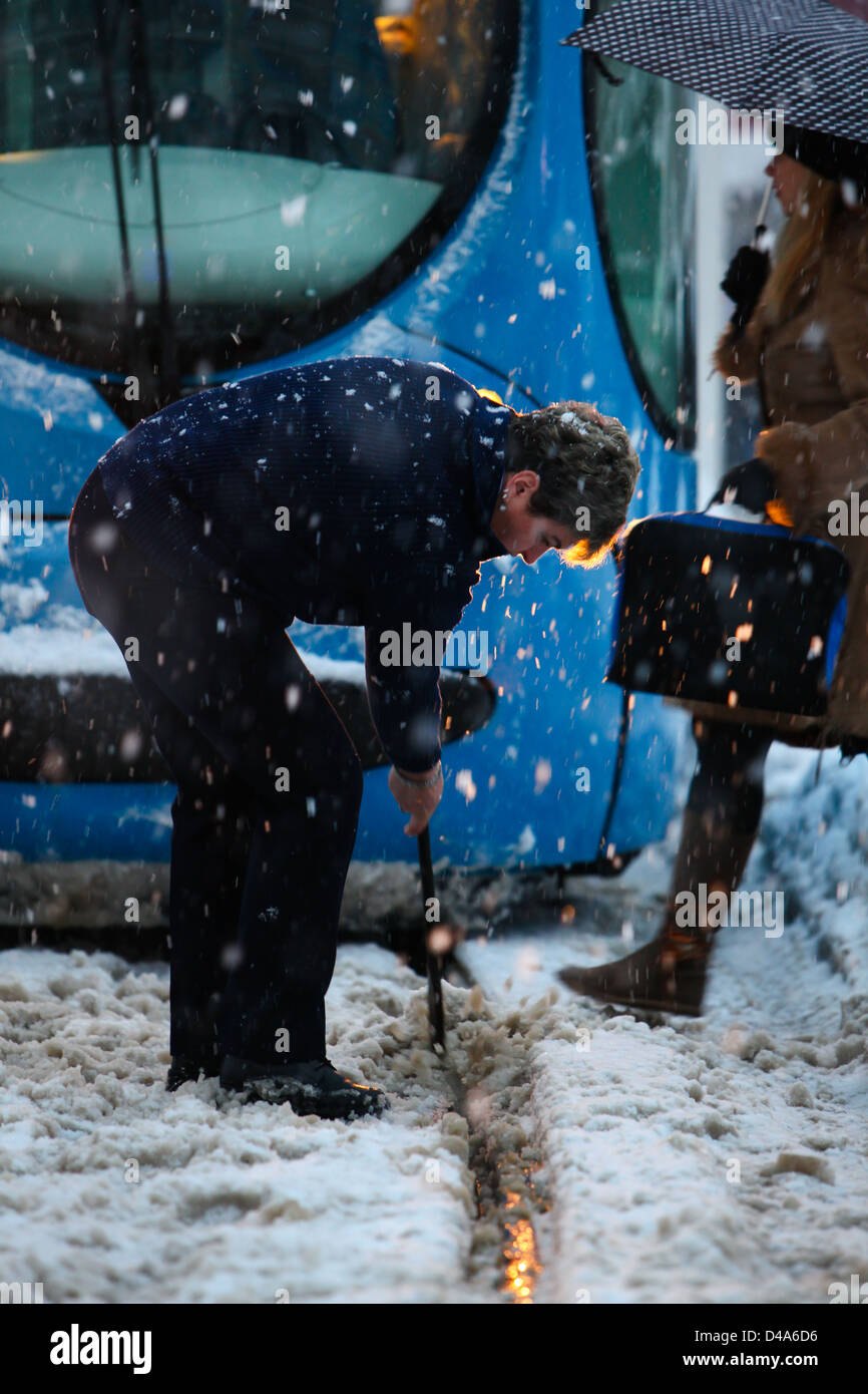 Female tram driver is cleaning rails while people are getting into tram ...