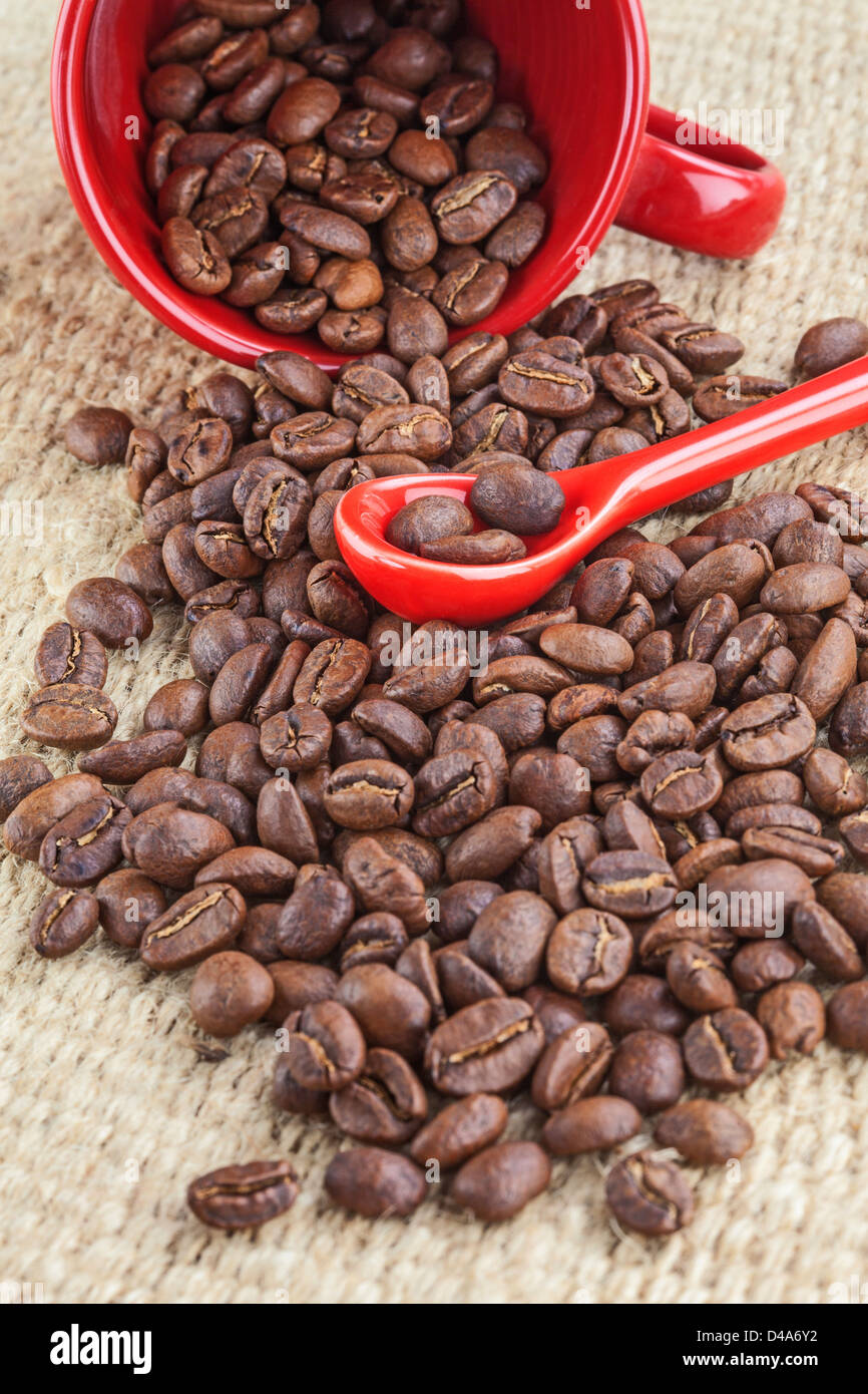 Spilled coffee seeds and red cup and spoon Stock Photo - Alamy