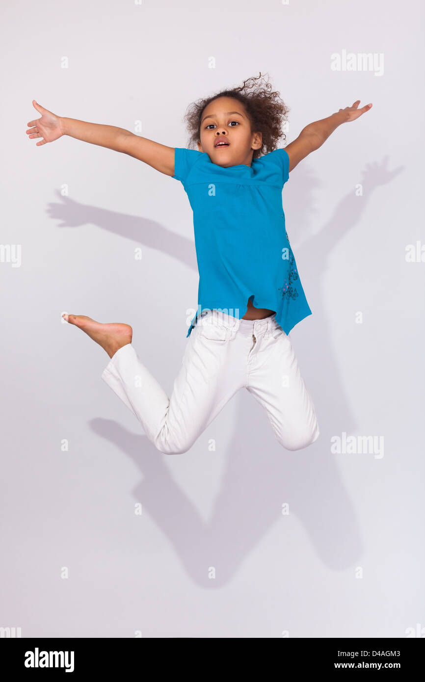 Portrait of cute Young African American girl jumping, over gray ...