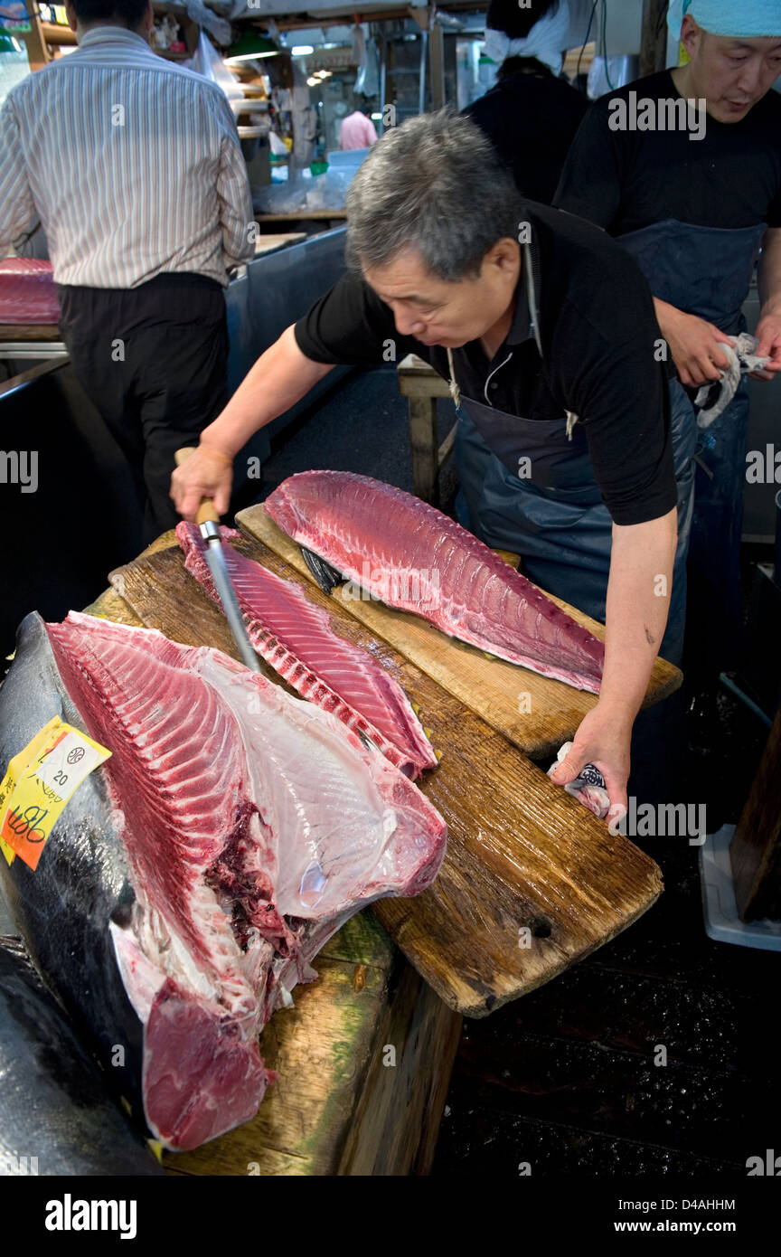 A fishmonger slices up a large fresh tuna with a sharp knife at Tsukiji ...