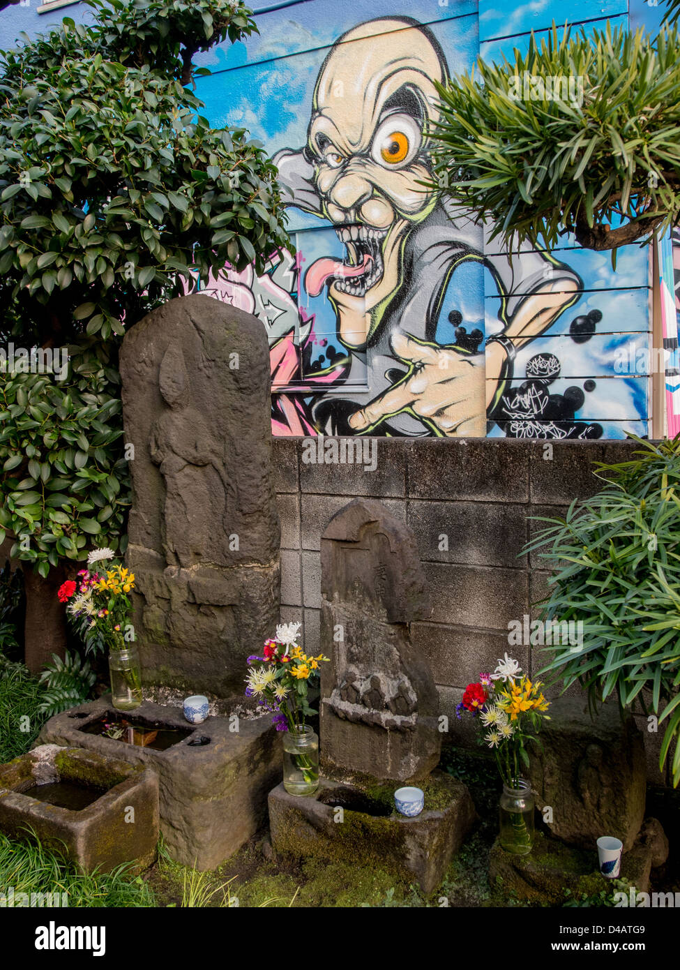 A graffiti monster looking down on buddhist statues in a small temple ...