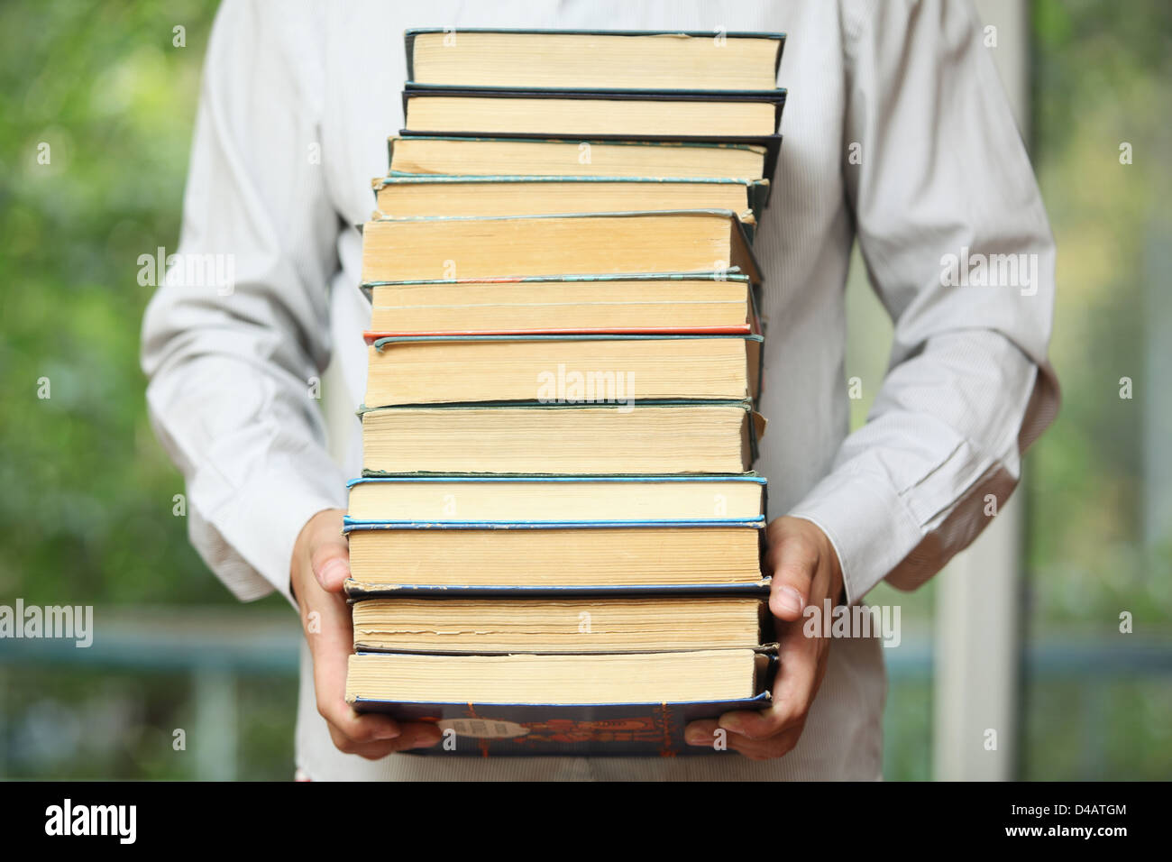 Guy in a shirt holding a stack of old books Stock Photo - Alamy