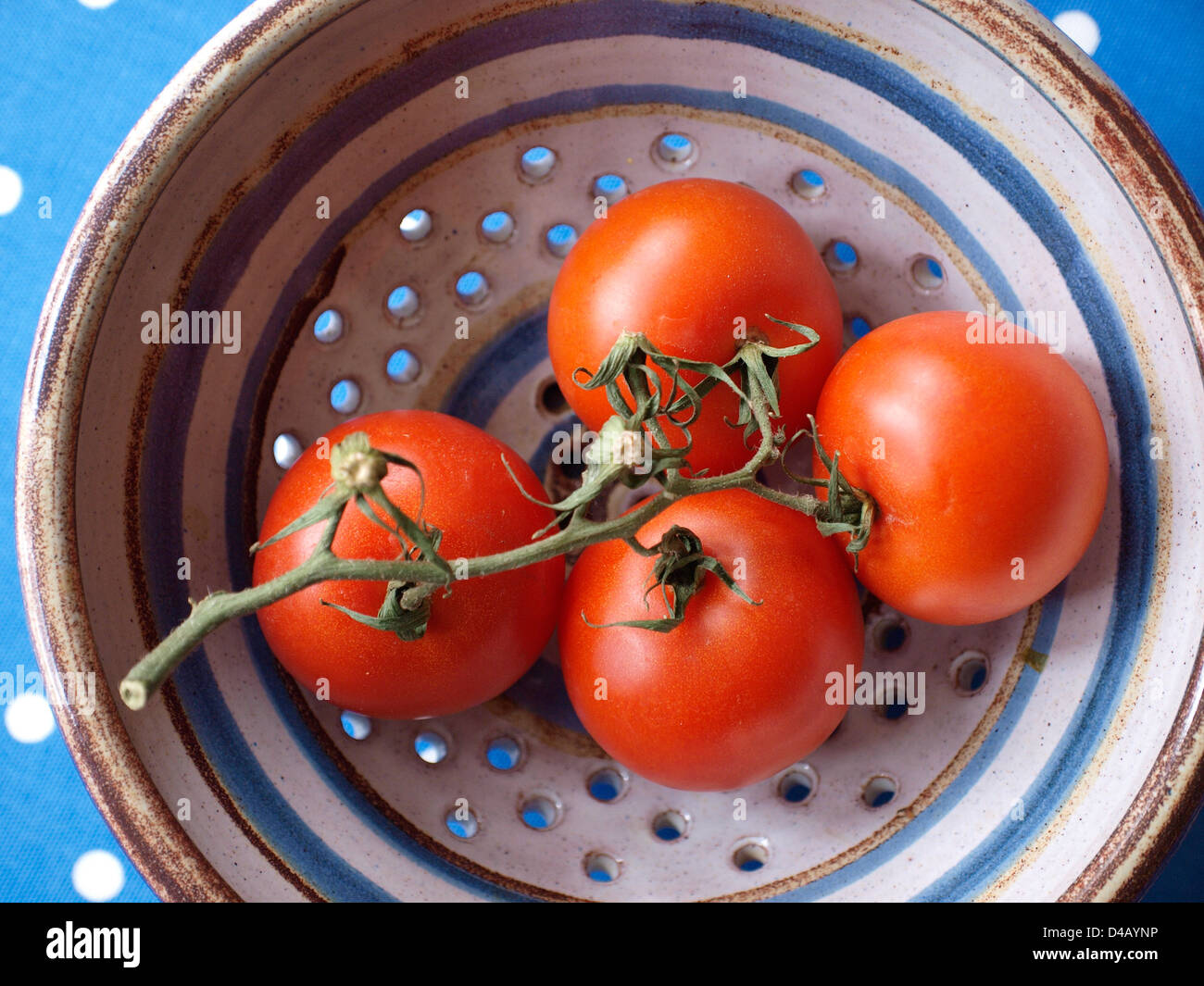 Four vine tomatoes sitting in a ceramic colander Stock Photo - Alamy