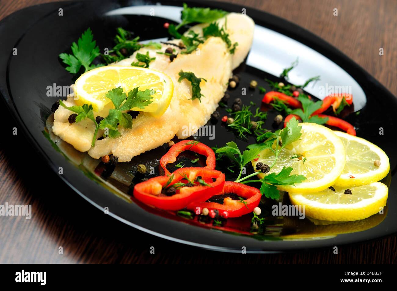 Black plate with grilled fish meat Stock Photo - Alamy