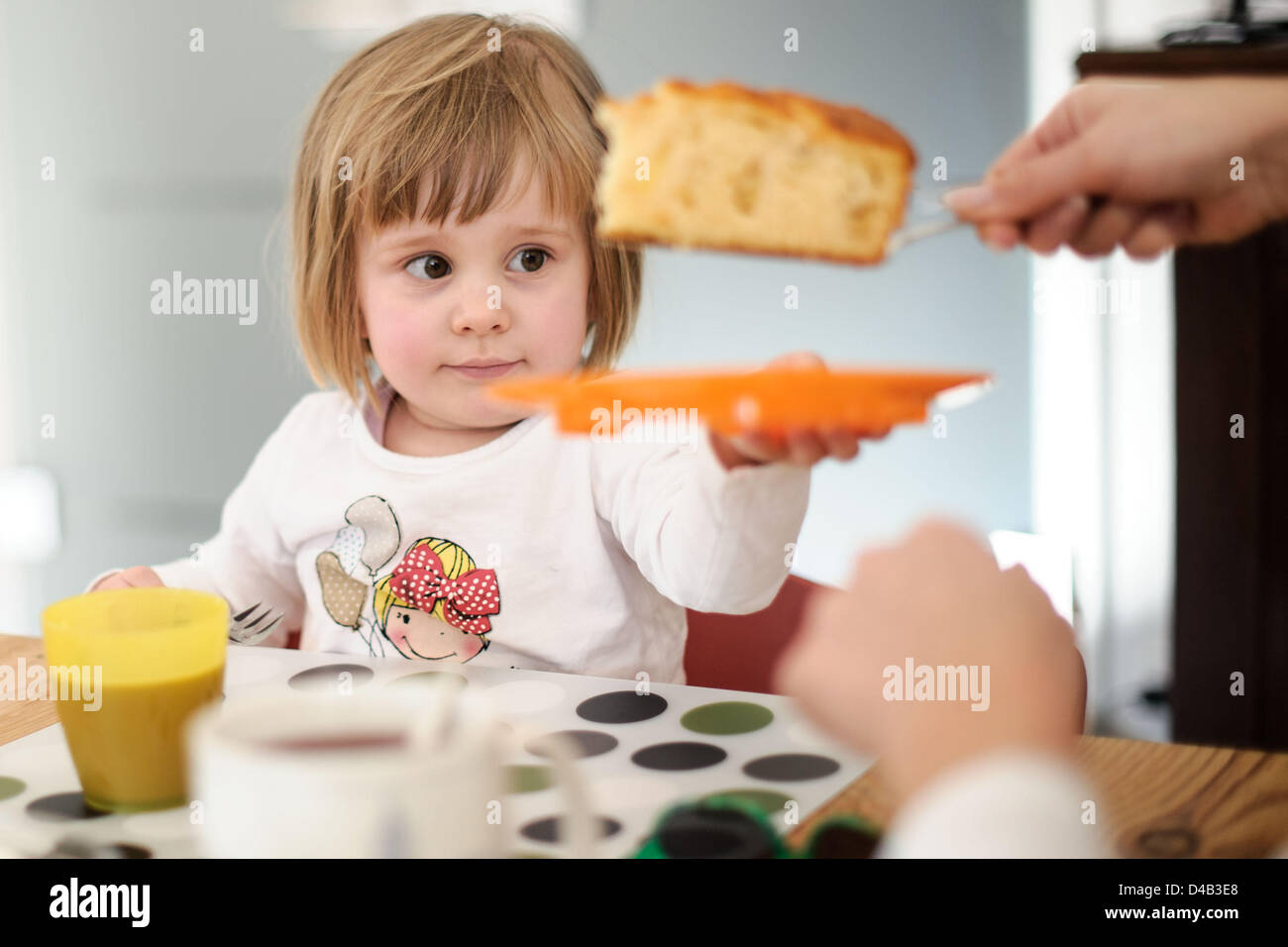 A young girl holds a plate in his hand, waiting for a piece of cake ...