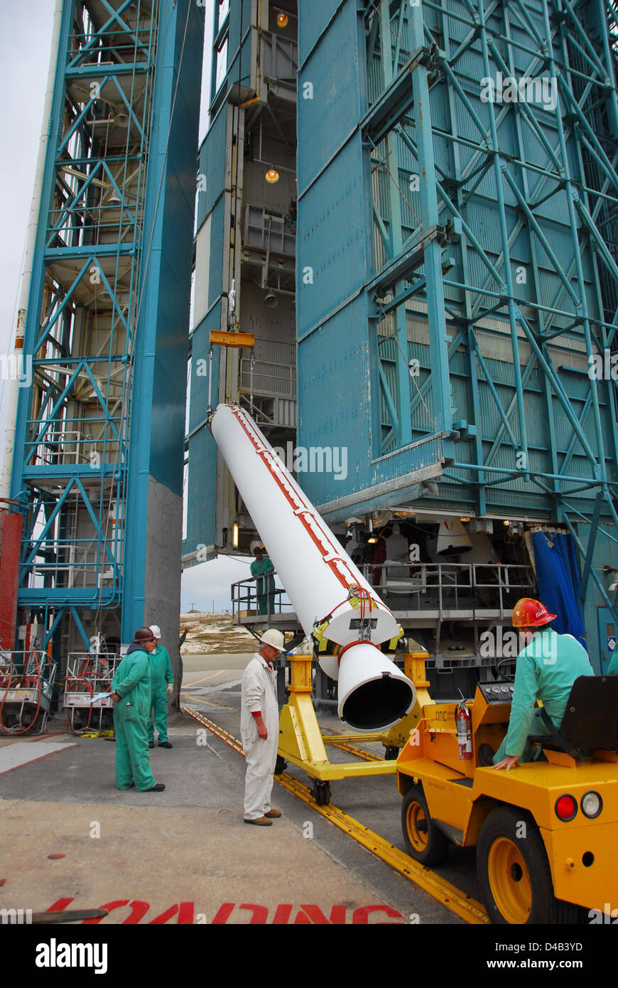 Technicians lift a solid rocket motor to the Delta II launch vehicle ...