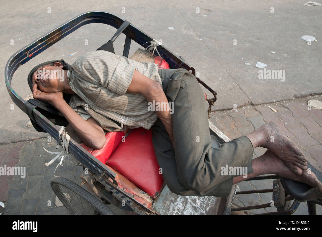 A rickshaw puller takes a quick nap on his rickshaw In Delhi, India ...