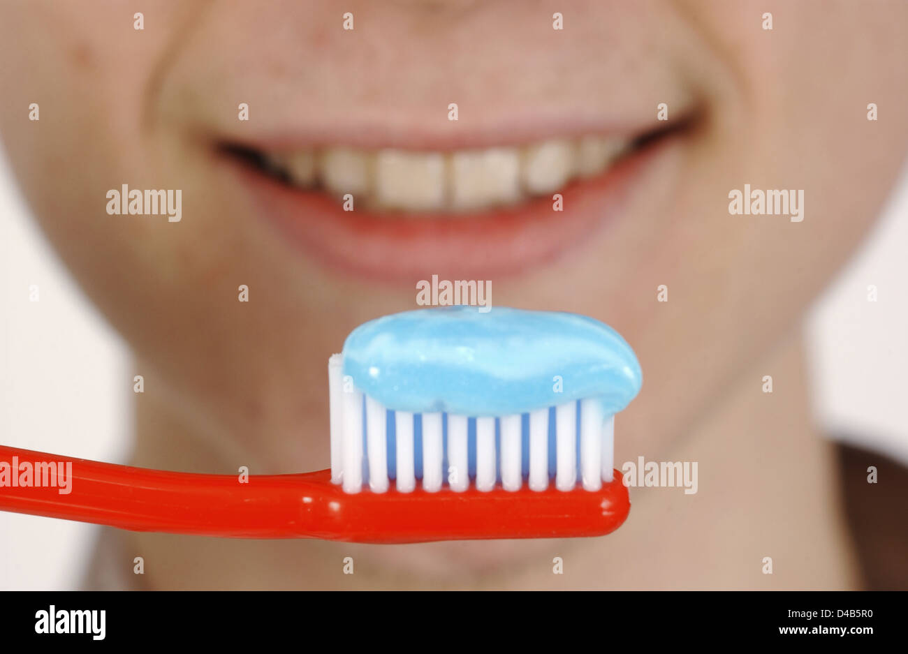 Man holding toothbrush with toothpaste on it on front of his teeth ...