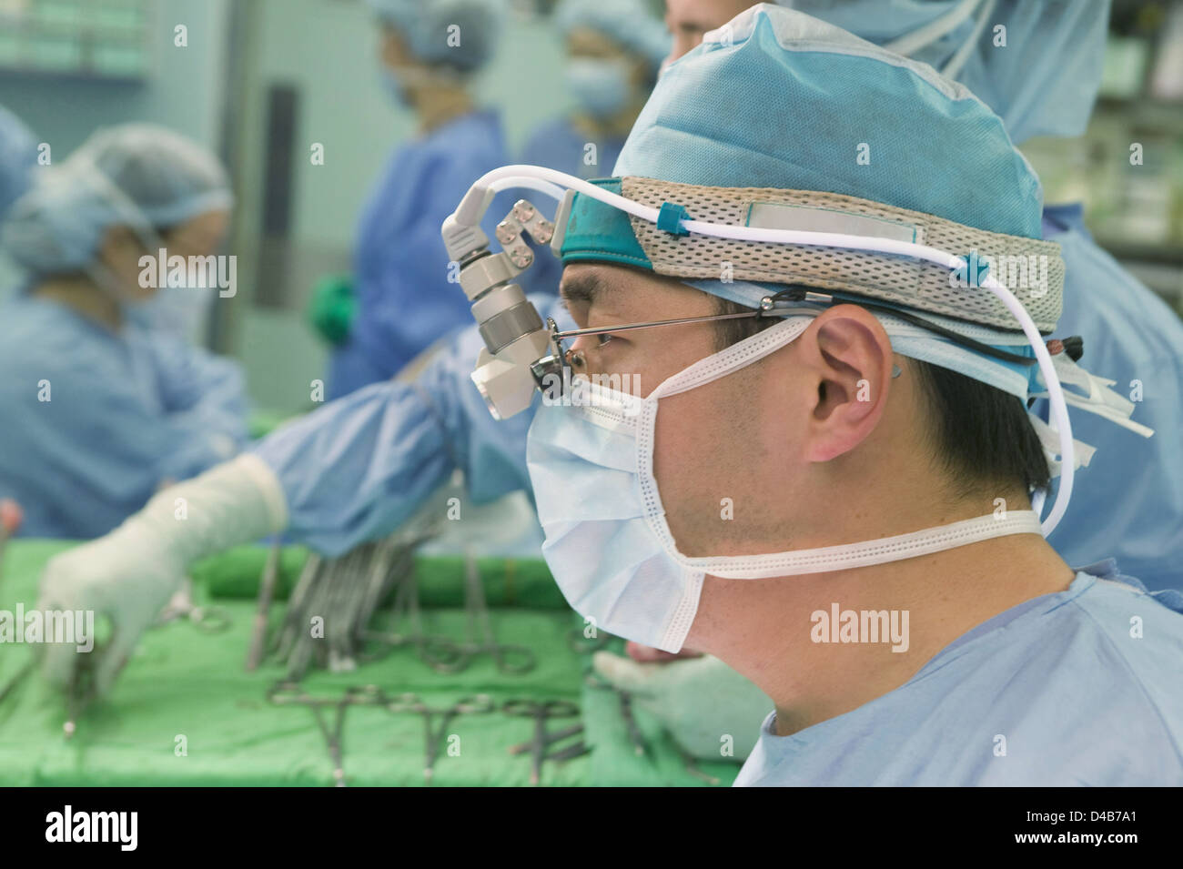 Profile of surgeon wearing binocular glasses to aid his vision whilst ...