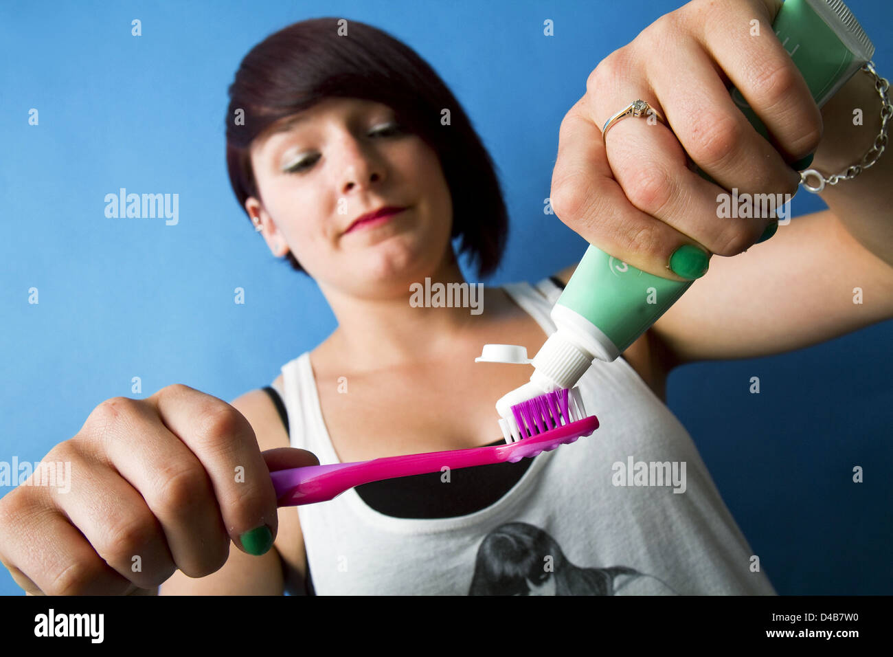 Young woman putting toothpaste on toothbrush Stock Photo - Alamy