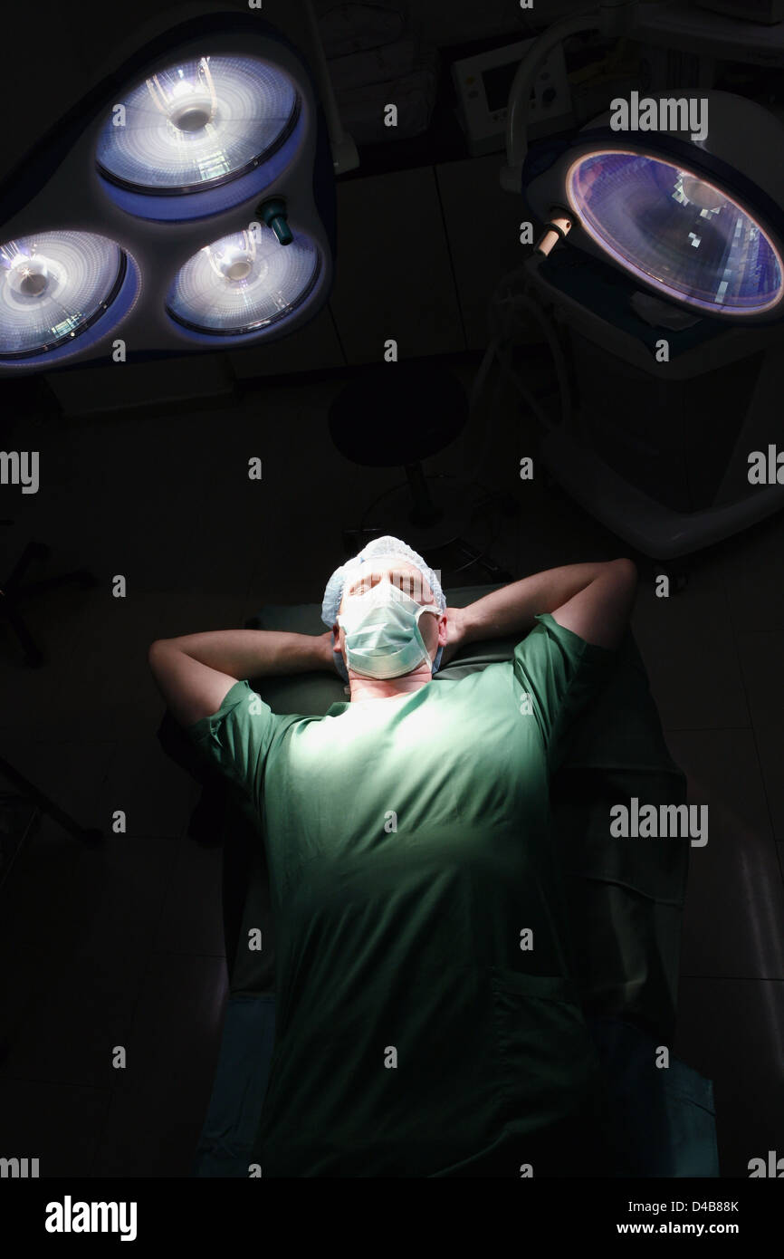 Tired surgeon sleeping on operating table, with his hands behind his ...