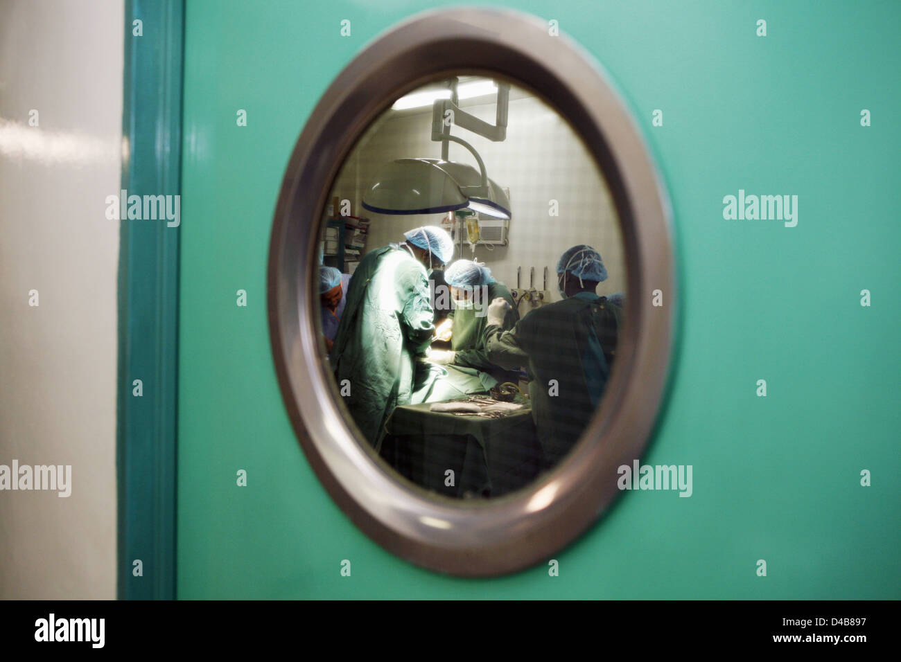 View through operating door window of surgical staff operating on ...