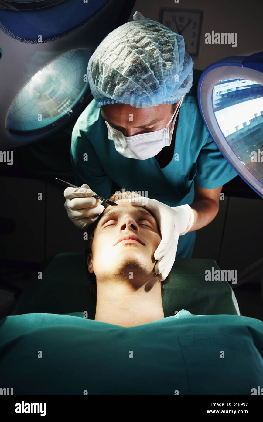 Surgeon preparing to make surgical incision into forehead of patient ...