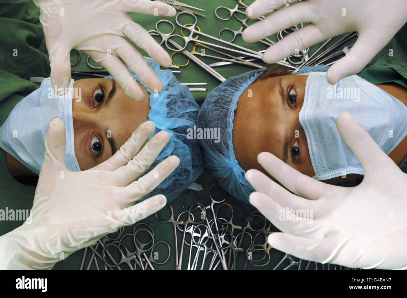Doctor and female nurse wearing green surgical gowns, caps, face masks ...