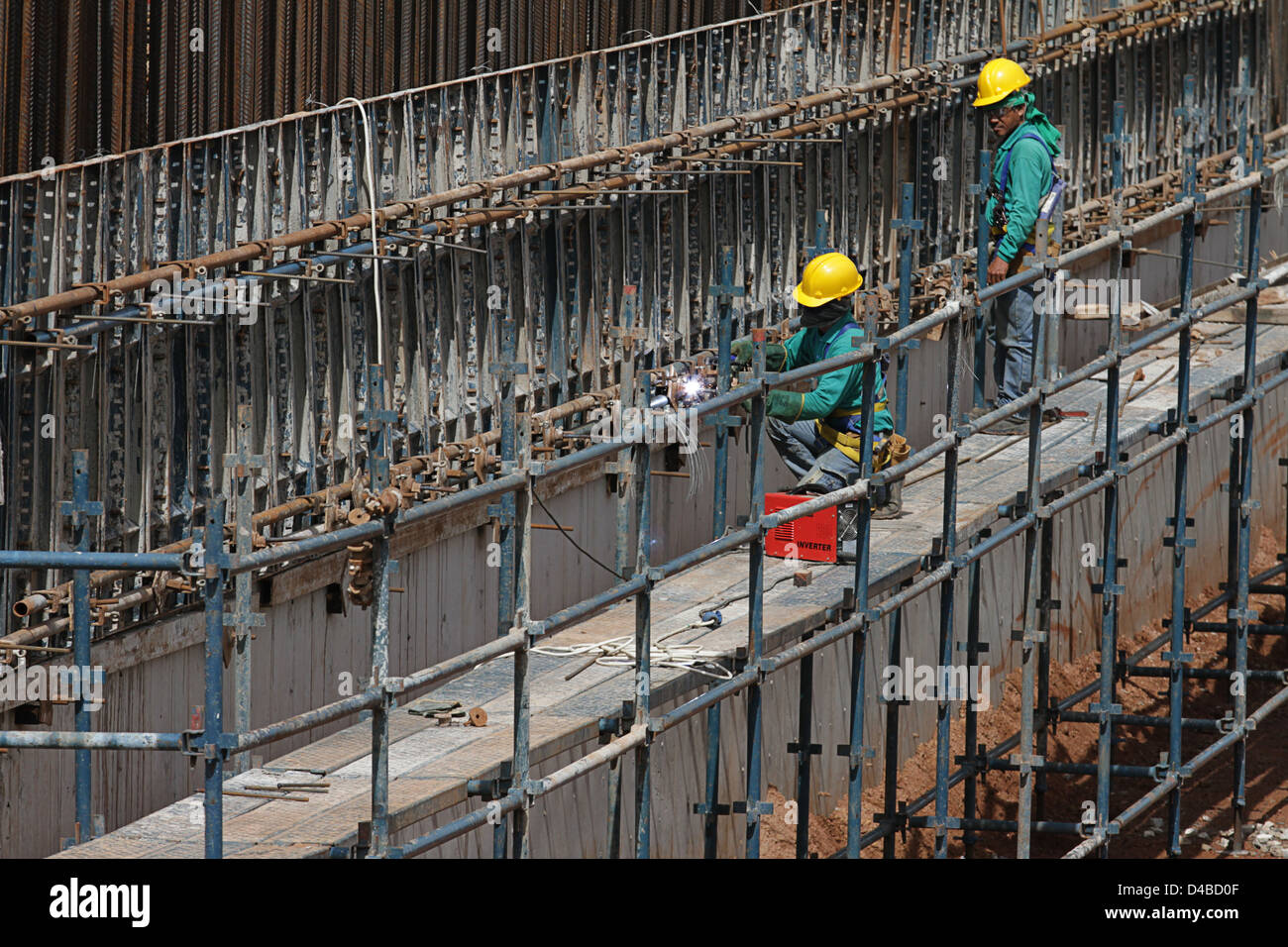 Two employees working on scaffolding and welding metal support rods ...